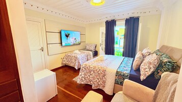 Quarto com duas camas, televisão, janela com cortinas e porta.