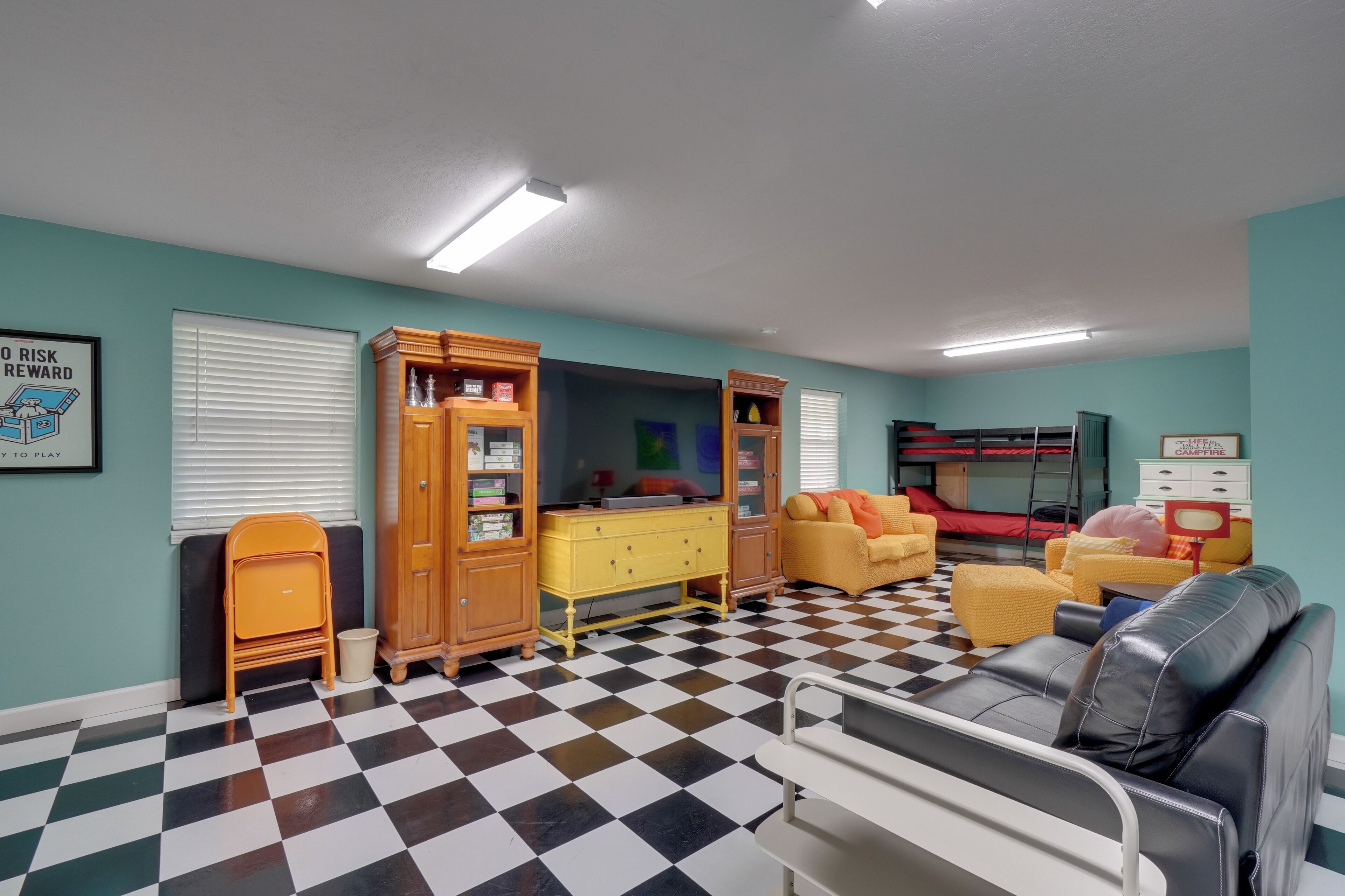 Um quarto com piso xadrez, uma cama, um sofá, um armário e uma televisão.