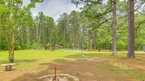 Uma área arborizada com uma cabana pequena, uma rede de voleibol e um tee de disc golf.