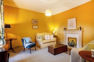 Sala de estar com sofá, poltrona, lareira e abajur.