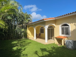 Uma casa com telhado de cerâmica, varanda coberta e gramado.
