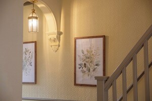 Escada com luminária e arte botânica emoldurada na parede.