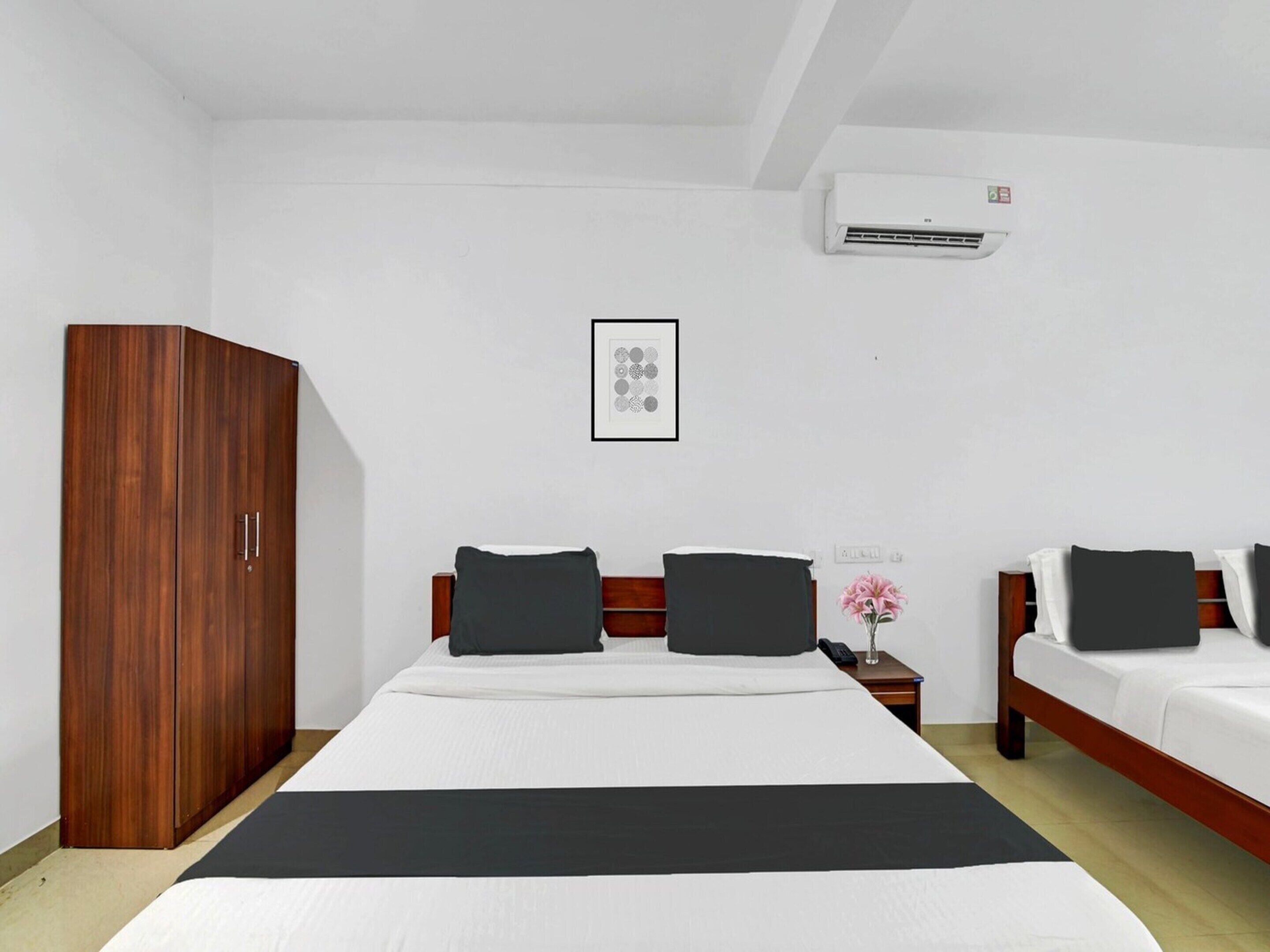 Quarto com cama, duas mesas de cabeceira, guarda-roupa, ar condicionado e um quadro na parede.