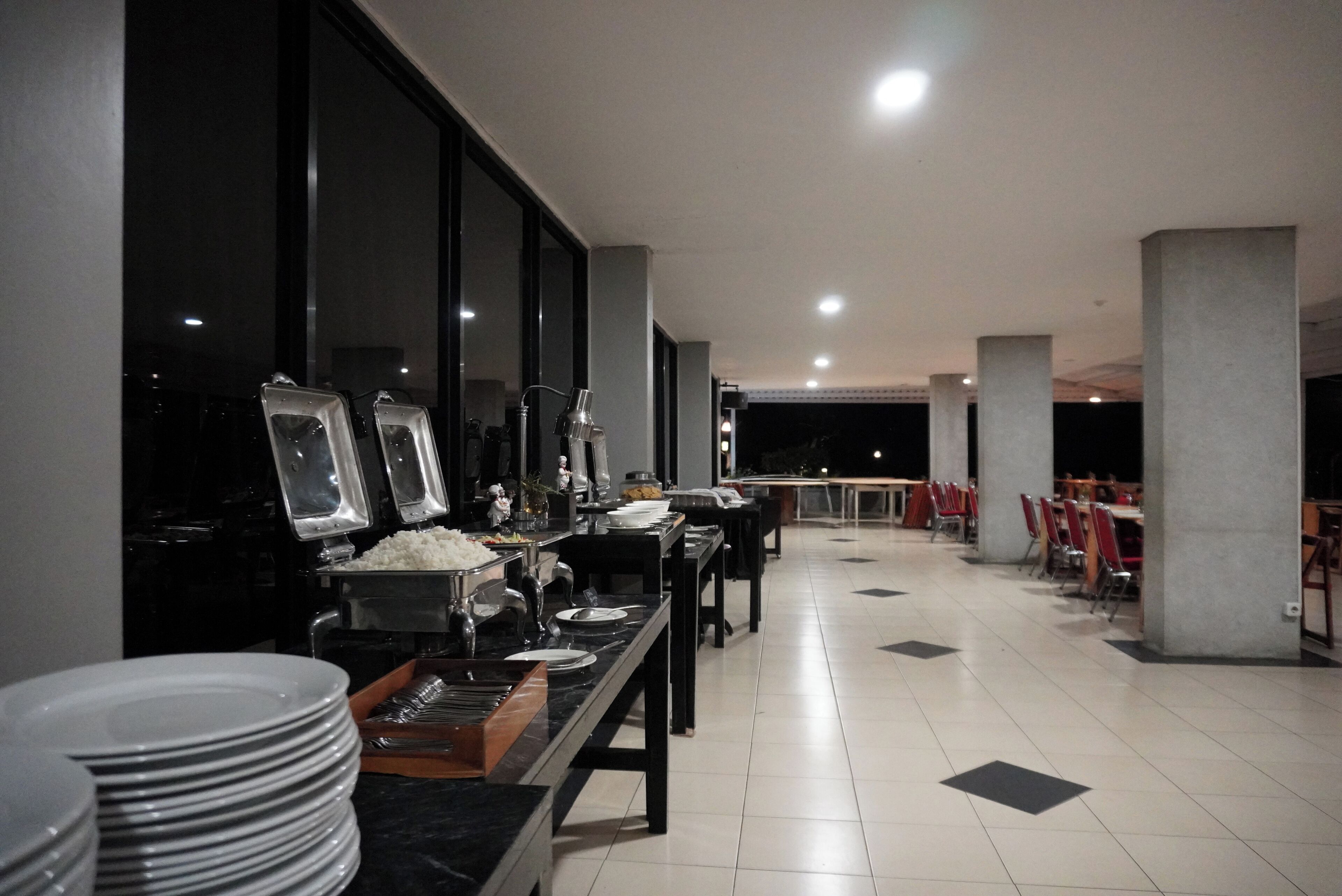 Uma disposição de buffet com várias estações de serviço, um balcão longo e uma área de jantar com cadeiras e mesas.