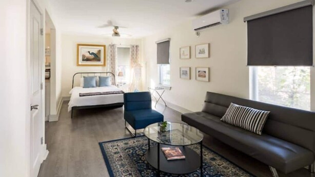 Quarto moderno com cama, sofá, mesa de centro e janela com vista.