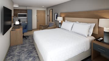 Quarto de hotel com uma cama grande, uma mesa de trabalho, uma cozinha compacta e um espaço de estar.