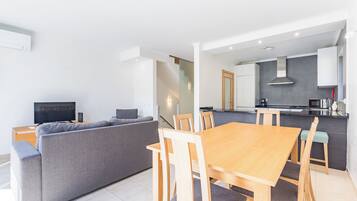 Uma sala de estar moderna com um sofá, uma mesa de jantar de madeira e uma área de cozinha com armários e um fogão.