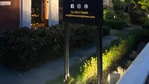 Placa para 'The Room's Boutique B&B & Licensed Cafe', com informações de contato e ícones de redes sociais.