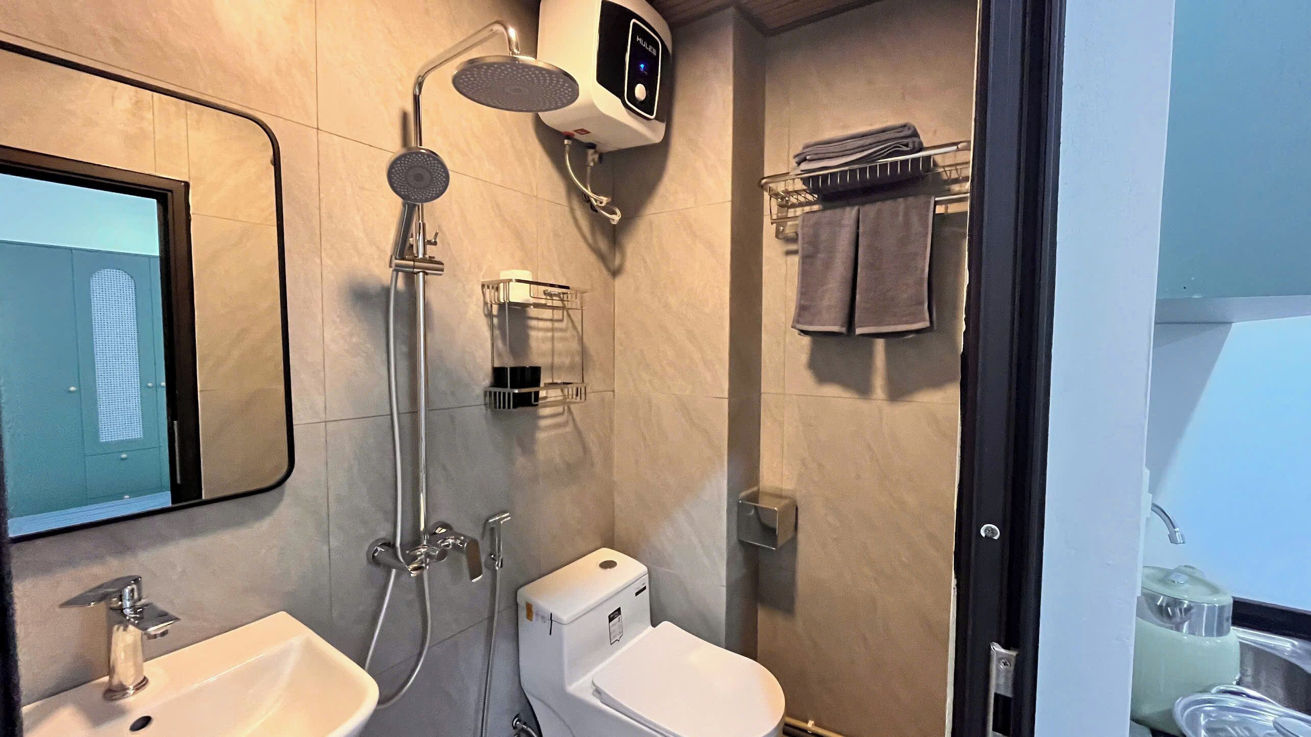 Uma casa de banho moderna com chuveiro, sanita, lavatório e um porta-toalhas.