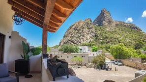 Uma varanda com vista para uma montanha, um cacto e um muro de pedra.