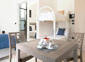 Quarto com uma cama de solteiro, uma mesa de jantar e uma bandeja com itens de café da manhã, além de uma cadeira.