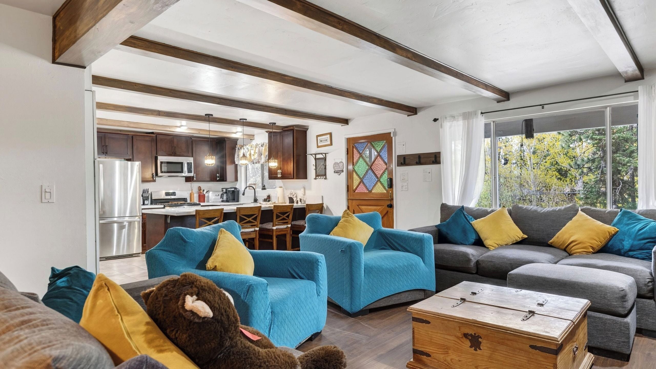 Uma sala de estar moderna com um sofá, cadeiras, uma decoração de urso e um baú de madeira.