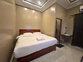 Quarto de hotel com cama grande, mesa de cabeceira, pia embutida e luminária no teto.