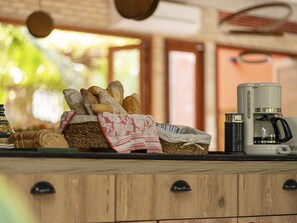 Uma bancada de cozinha com pão, uma cafeteira e uma cesta de vime.