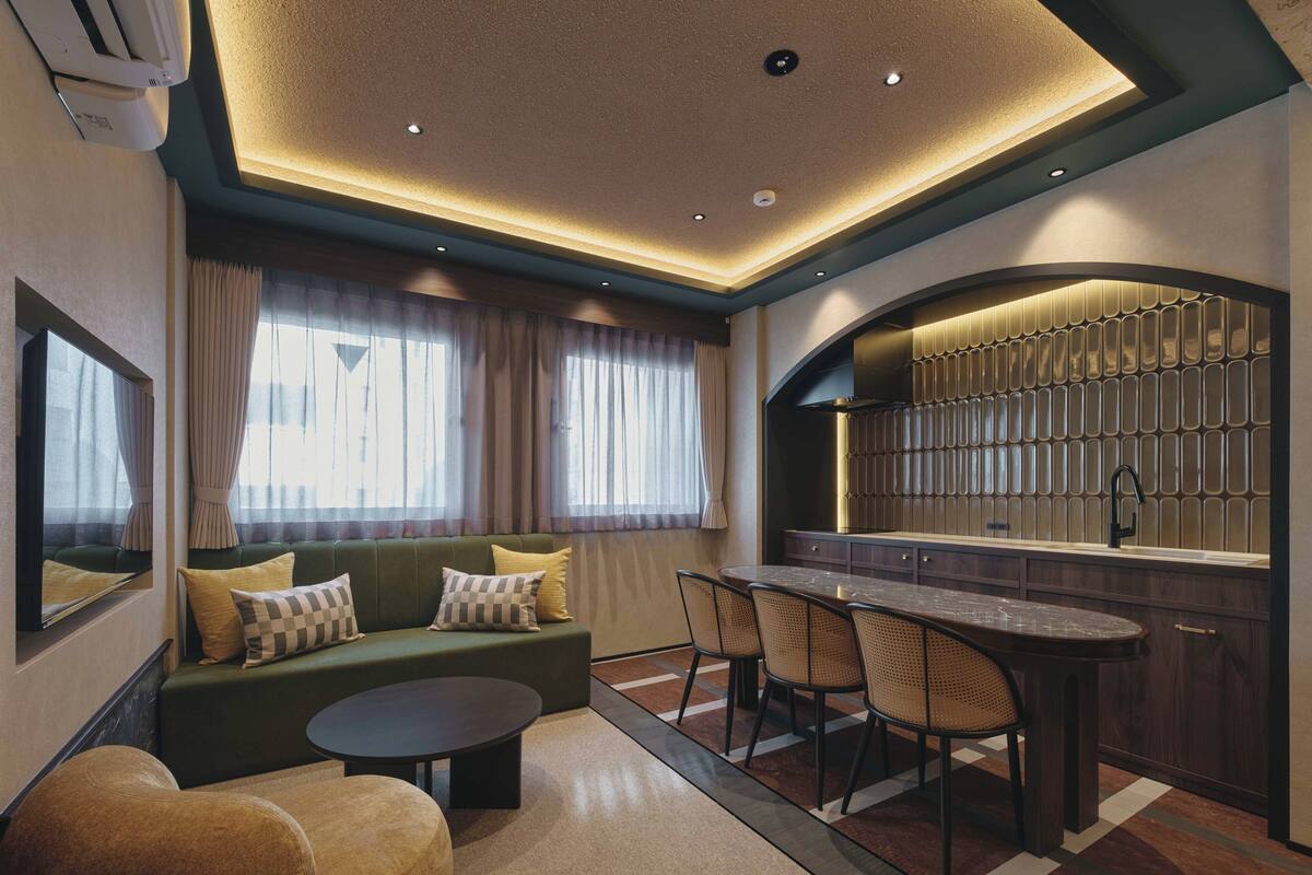 Quarto de hotel moderno com sofá, mesa redonda, bar e área de estar.