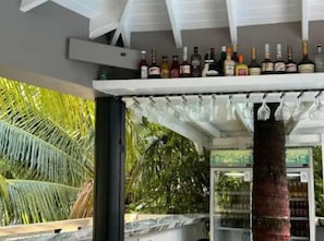 Uma área de bar com diversas garrafas de bebidas e copos.