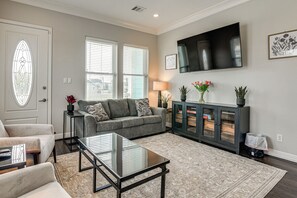 Sala de estar com sofá, mesa de centro, TV e objetos decorativos.