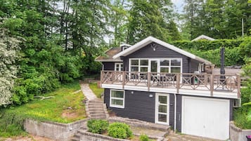 Uma casa de dois andares com varanda, garagem e área de jardim.