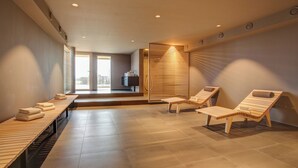 Um espaço de spa com espreguiçadeiras de madeira, piso aquecido e vista para a cidade.