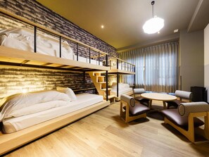 Quarto de hotel moderno com beliche, sofá, mesa de jantar e escada.