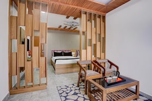 Quarto com cama, mobiliário de madeira, ventoinha no teto e piso ladrilhado.