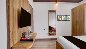 Quarto moderno com toucador de madeira, televisão de tela plana, cama e espelho.