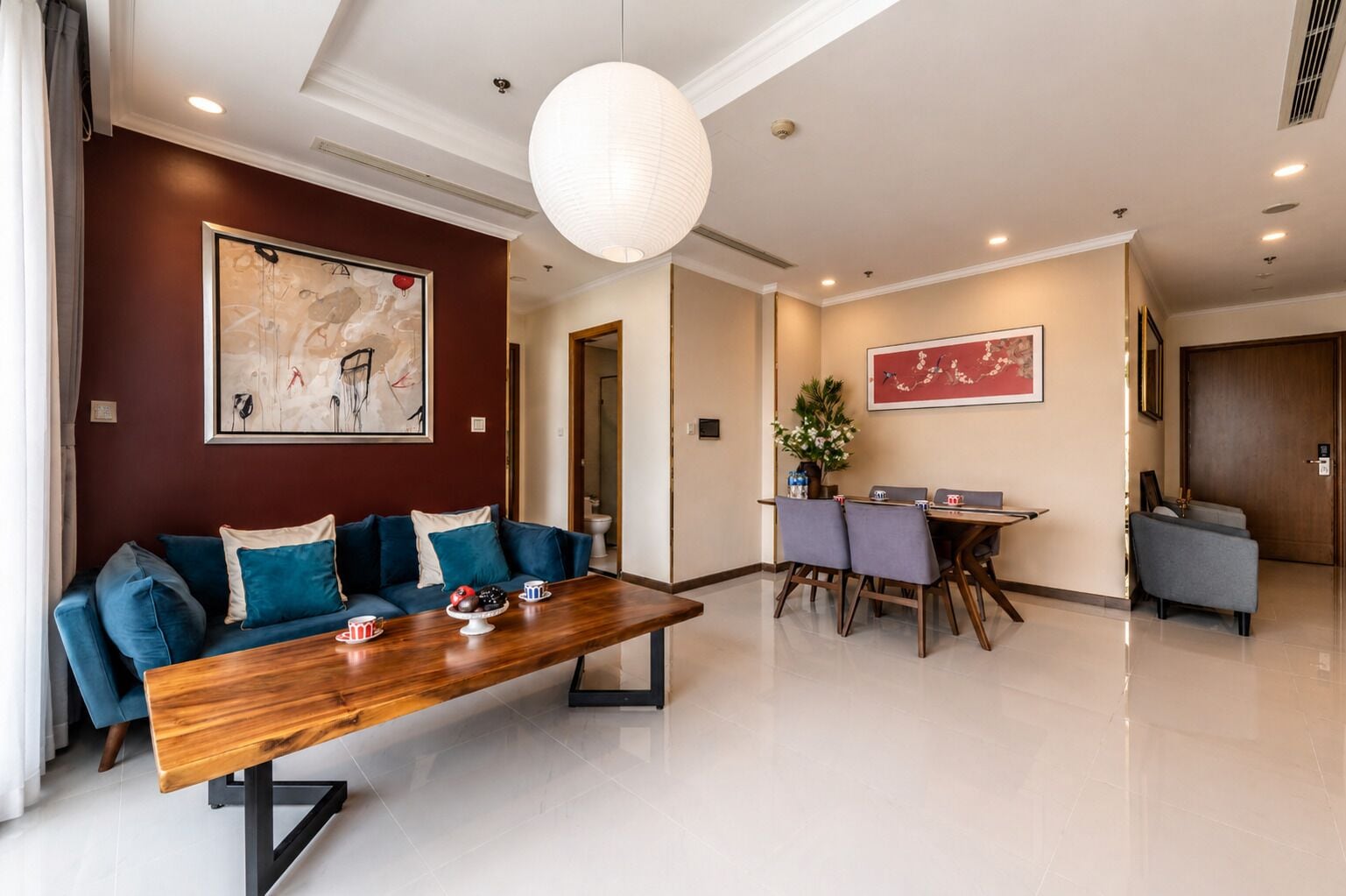 Uma sala de estar moderna com uma mesa de centro de madeira, sofá azul e um espaço de refeições com mesa e cadeiras.