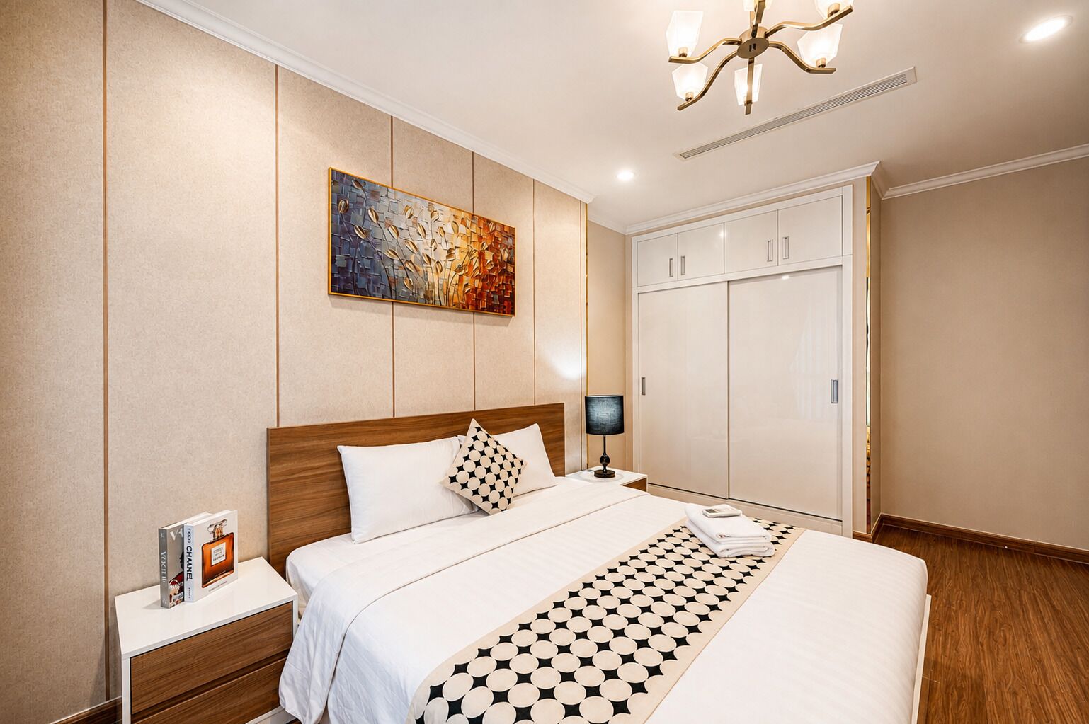 Quarto de hotel com cama, mesa de cabeceira, abajur, guarda-roupa e um quadro na parede.