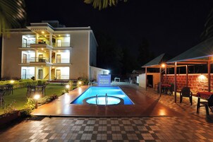 Um hotel com vários andares, piscina, área de estar ao ar livre e uma placa com a inscrição 'Prince Palace'.