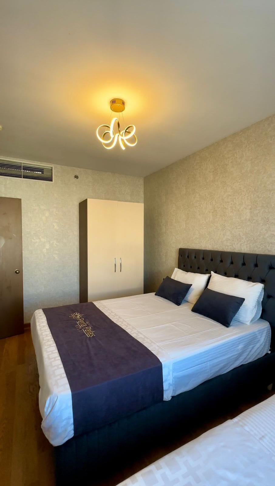 Quarto de hotel com cama, guarda-roupa e luminária no teto.