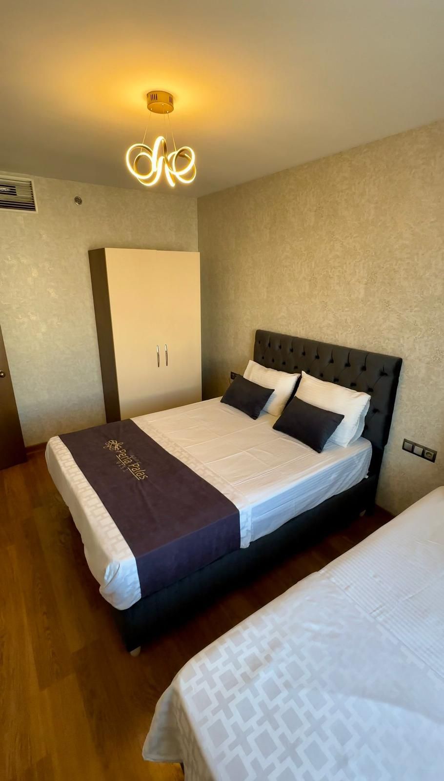 Quarto de hotel com uma cama, guarda-roupa e luminária no teto.
