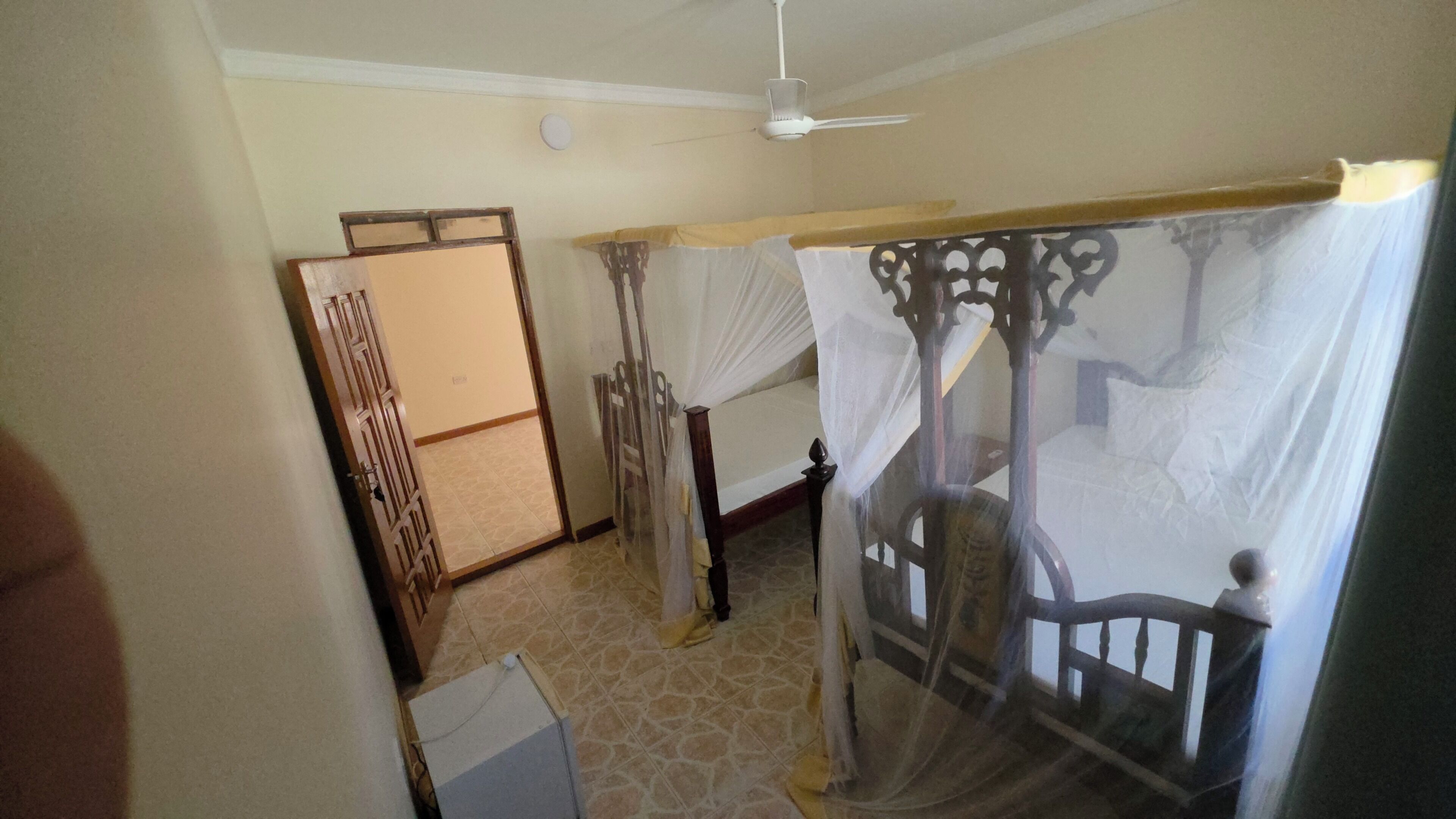 Um quarto com uma cama, um ventilador de teto e uma porta.