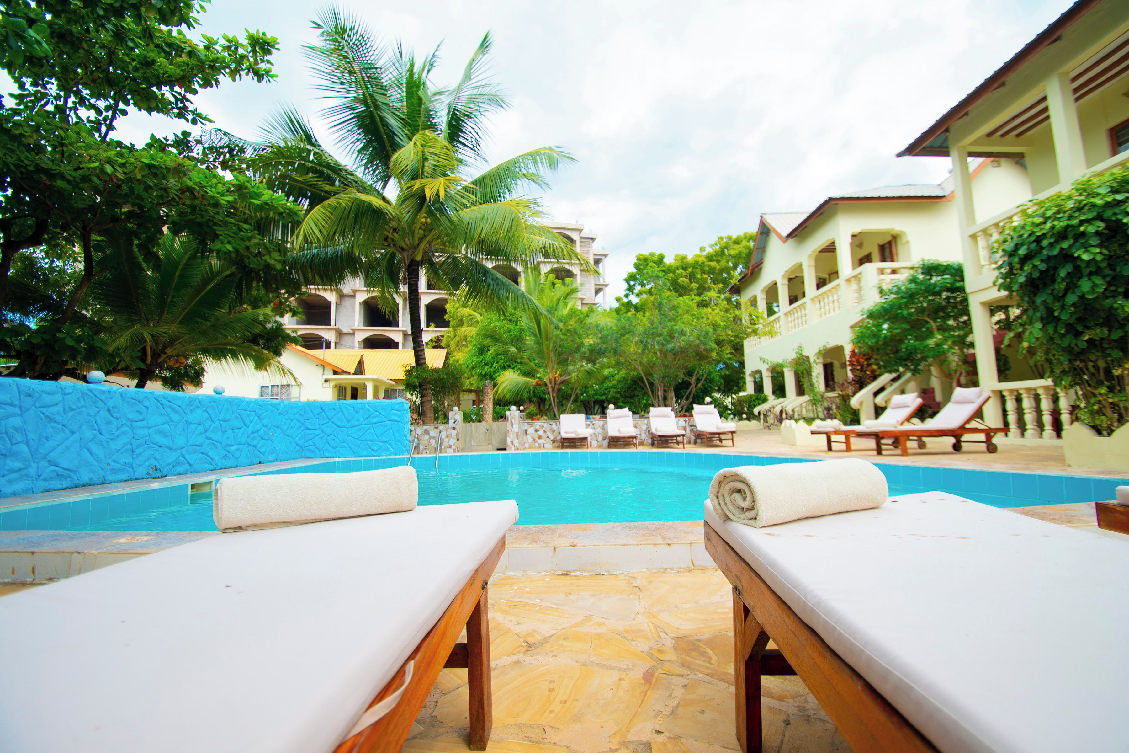 Uma área de piscina com espreguiçadeiras, piscina e um edifício com varandas.