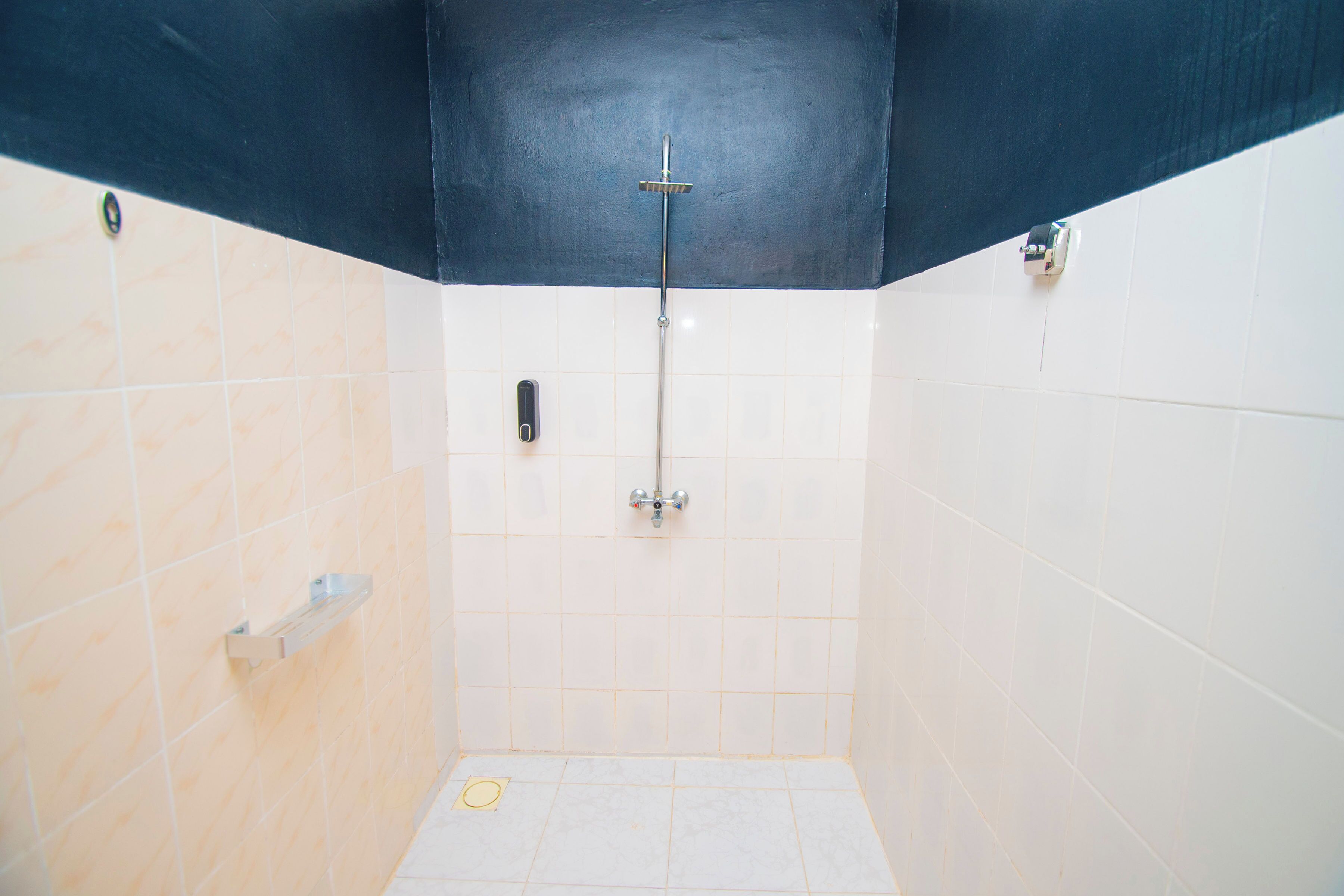 Um espaço de chuveiro pequeno revestido com azulejos, com chuveiro manual e torneira na parede.