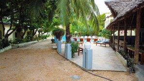 Um pátio com área de estar ao ar livre, piscina e vegetação tropical.