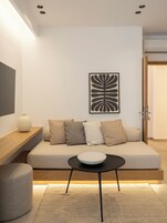Uma sala de estar moderna com um sofá, uma mesa de centro, um elemento decorativo na parede e uma prateleira de madeira com um vaso.