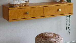 Um console de madeira com um espelho redondo, uma cesta de vime e uma planta em vaso.