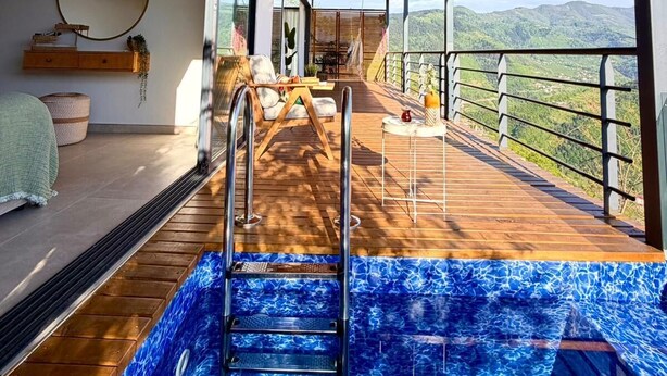 Interior moderno com teto de madeira, área de piscina e varanda com vista para as montanhas.