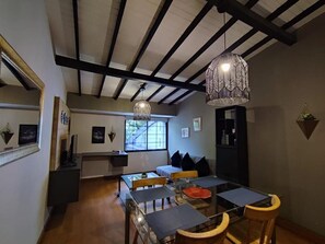 Uma área de refeições com mesa de vidro, cadeiras e iluminação pendente.