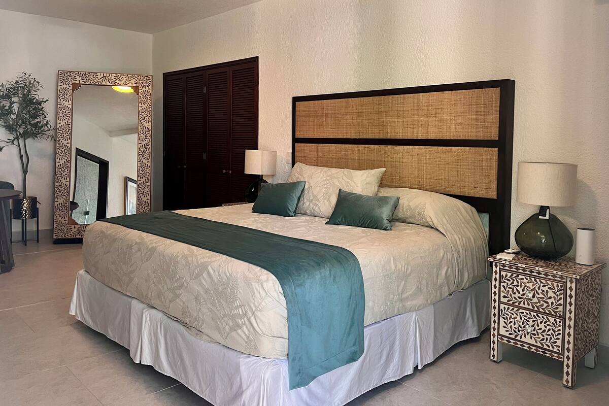 Quarto bem arrumado com cama grande, mesas de cabeceira, um espelho e porta com moldura decorativa.