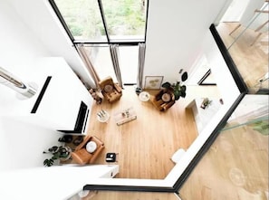Um interior moderno com piso de madeira, um sofá, uma mesa de centro e uma pequena planta.