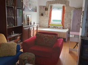 Um quarto com sofá vermelho, cadeira azul, estante de livros, lareira e janela com cortinas.