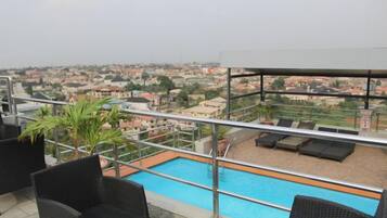 Área de piscina no terraço, com espreguiçadeiras e vista para a paisagem urbana.