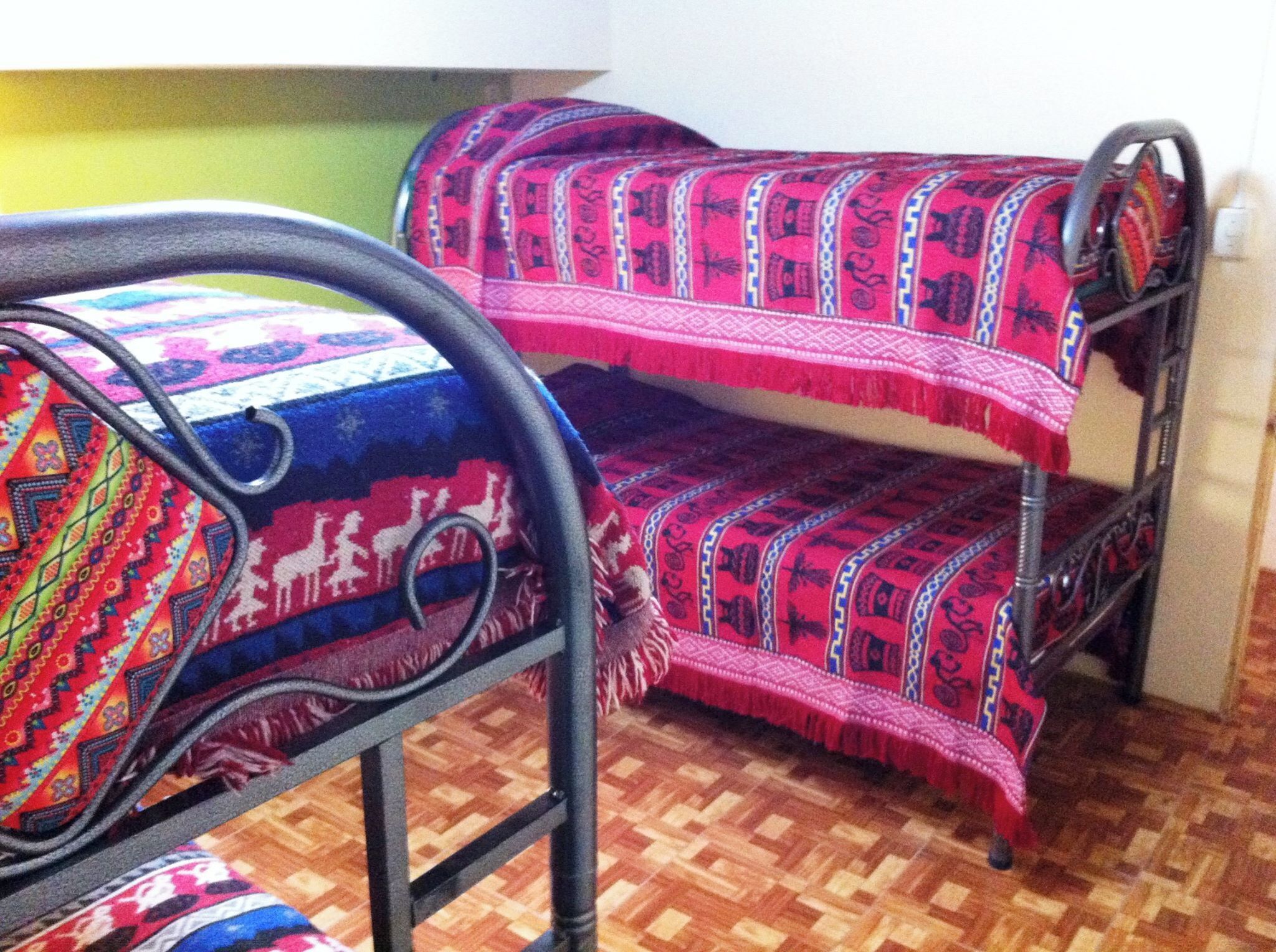 Uma cama beliche com roupa de cama colorida e estrutura de metal.