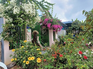 Um jardim com diversas plantas floridas e uma escultura de madeira.