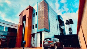 Um edifício moderno com fachada geométrica, área de estacionamento com piso padronizado e céu claro.