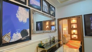 Um quarto com um espelho grande, quadros emoldurados, uma mesinha de consola, um sofá e um tapete estampado.