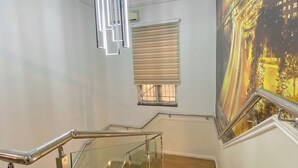 Uma escadaria moderna com guarda-corrimãos de vidro e um mural com vista para a cidade.