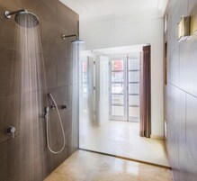 Uma casa de banho moderna com chuveiro, sanita e porta de vidro para uma varanda.