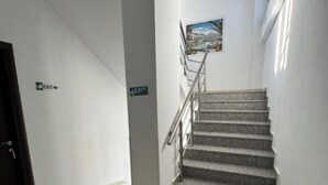 Uma escada com corrimão, uma placa indicando uma saída e um quadro na parede.